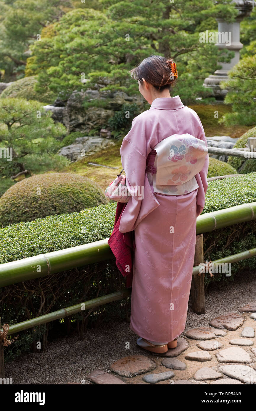 A woman visitor wearing a pink spring kimono in the gardens of the ...