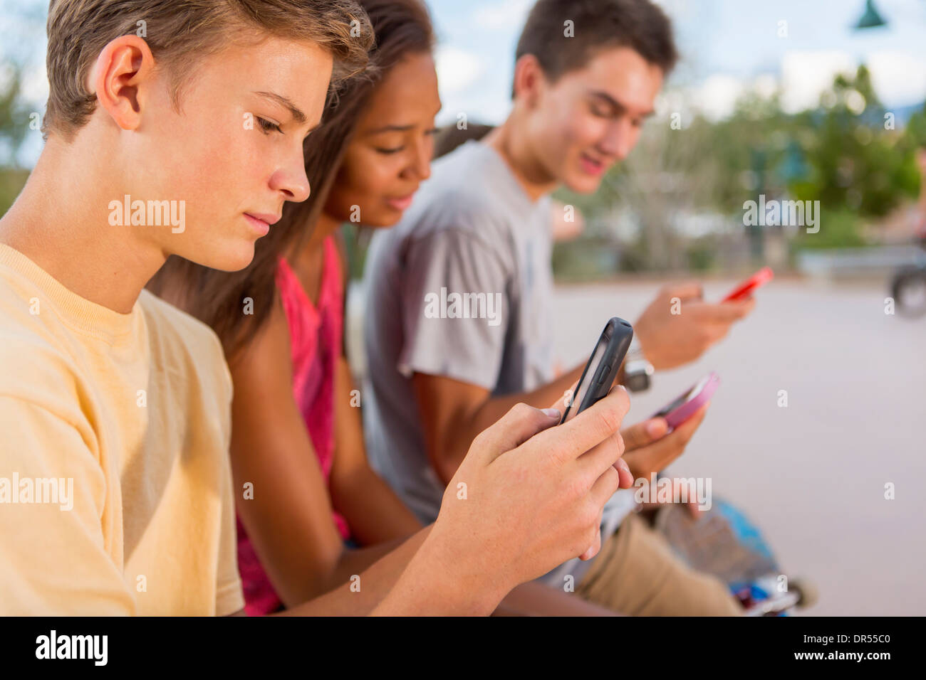 Teenagers using cell phones outdoors Stock Photo - Alamy