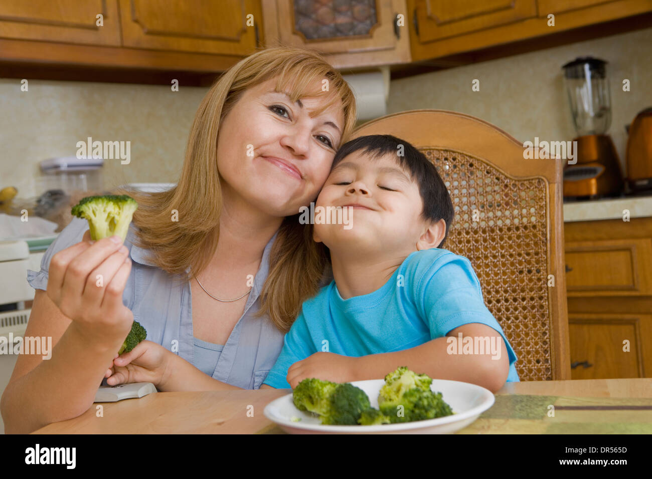 Hispanic mother and son eating broccoli Stock Photo - Alamy
