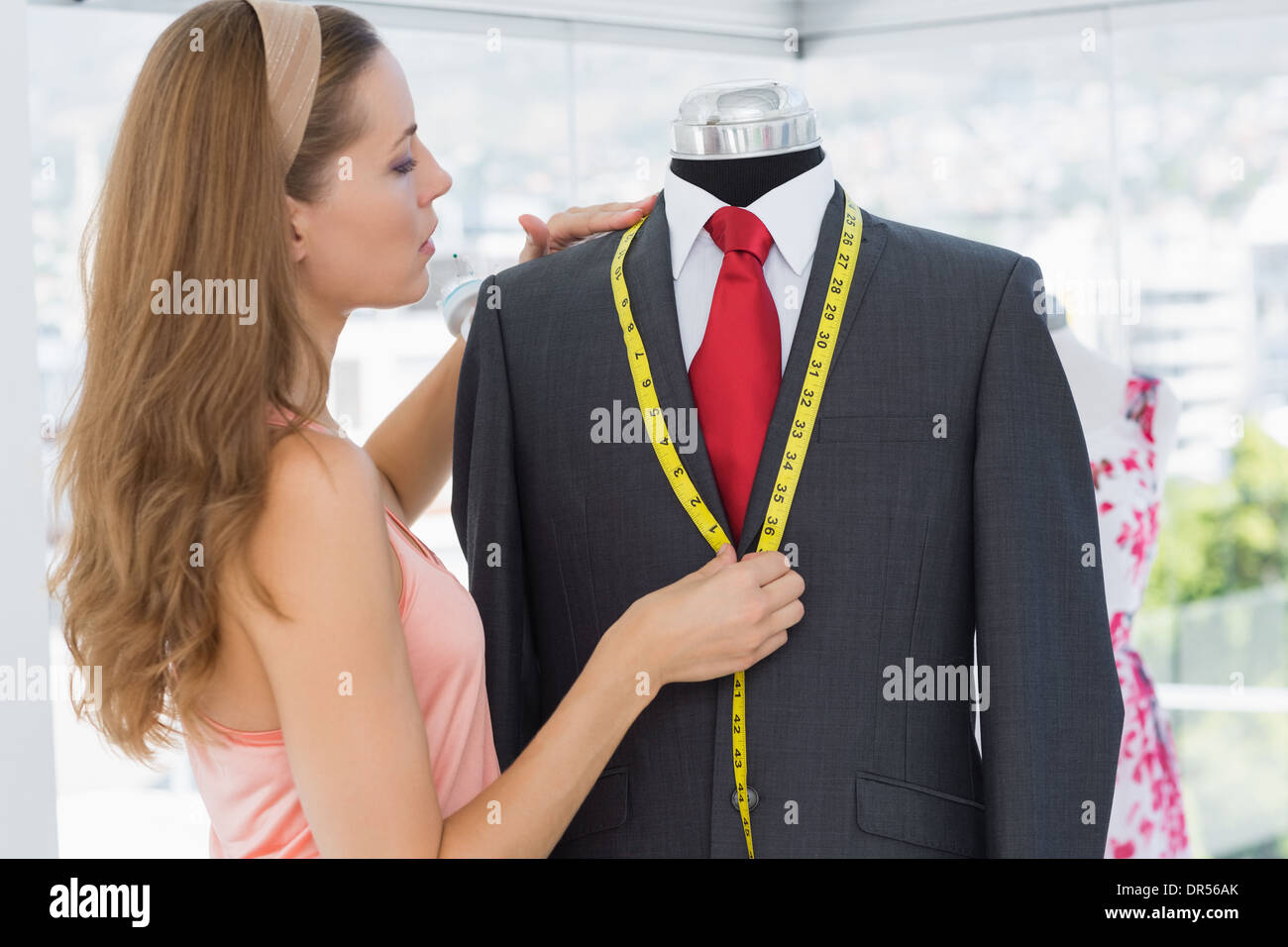 Female fashion designer measuring suit on dummy Stock Photo - Alamy