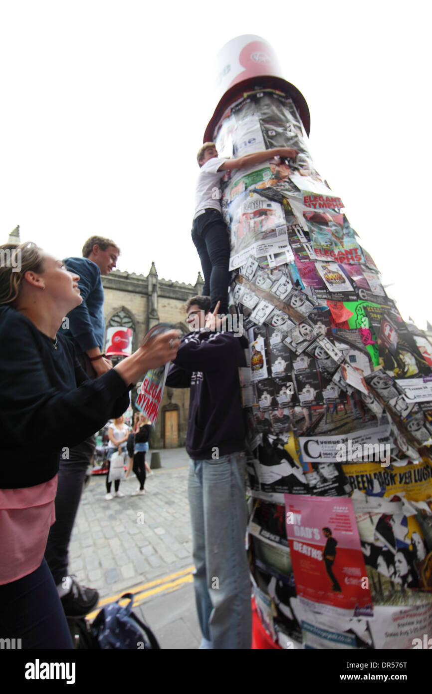 Students form a human ladder to post a fringe advertising poster bill ...
