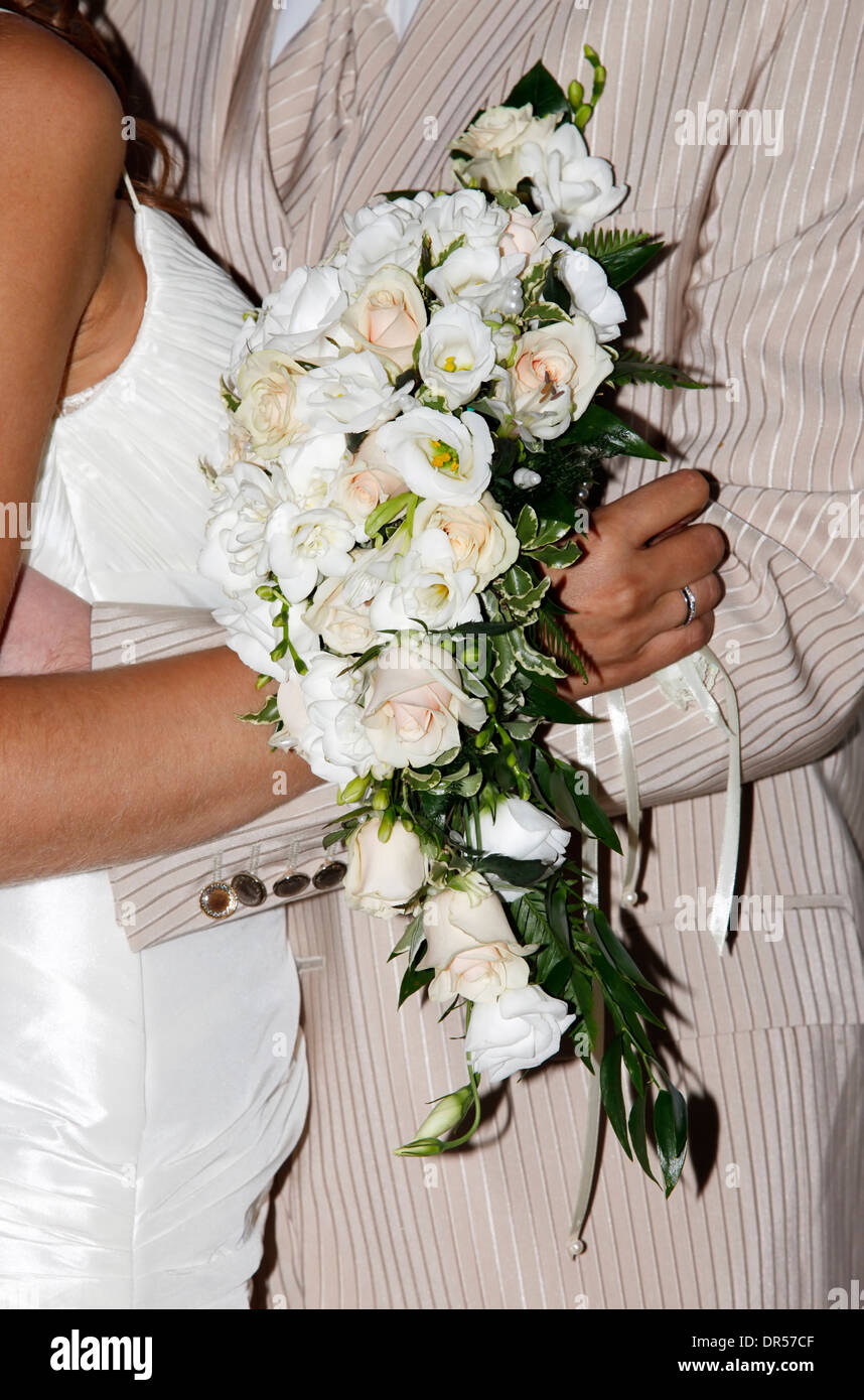 Bouquet of flowers on a background of a dress of the bride and a suit ...