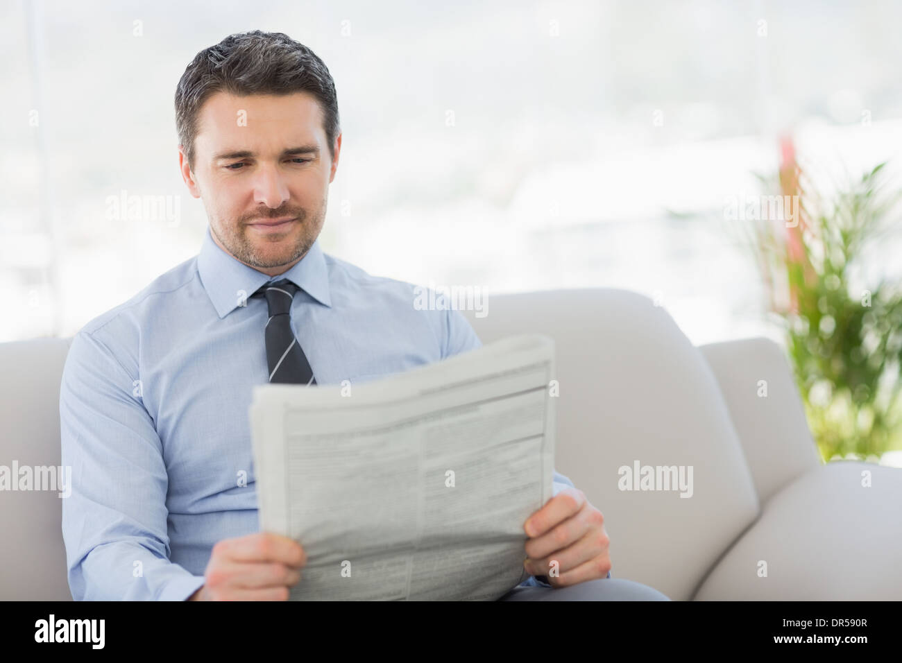 Well dressed man reading newspaper at home Stock Photo - Alamy