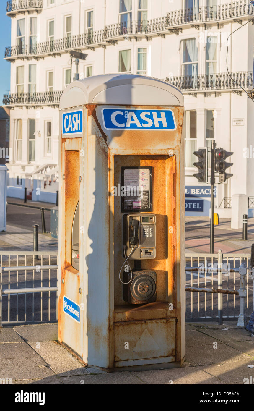 Rusty telephone box with payphone and cash dispenser on seafront in ...