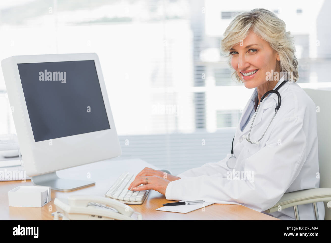 Female doctor using computer at desk in medical office Stock Photo - Alamy