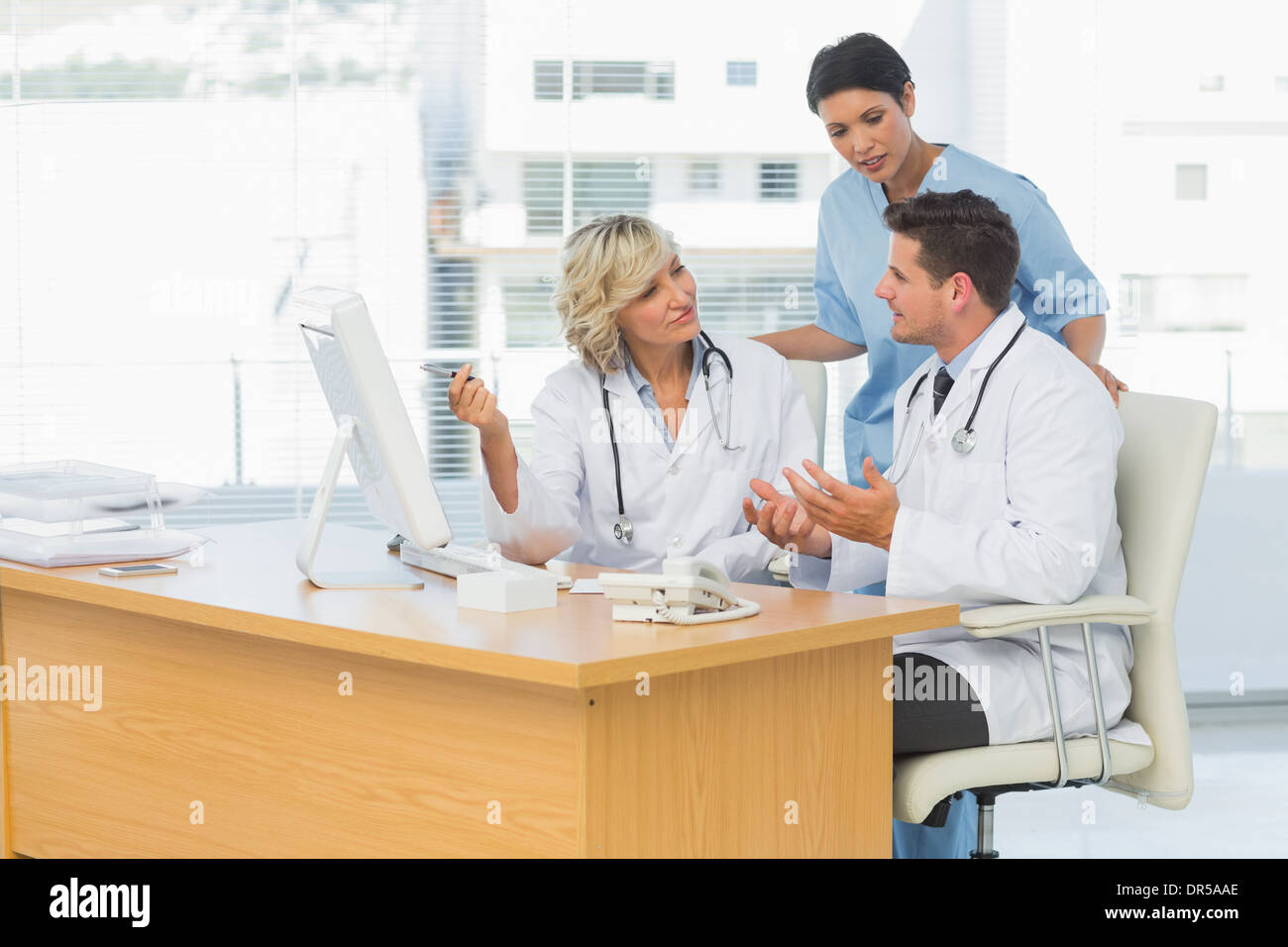Three concentrated doctors using computer together Stock Photo - Alamy