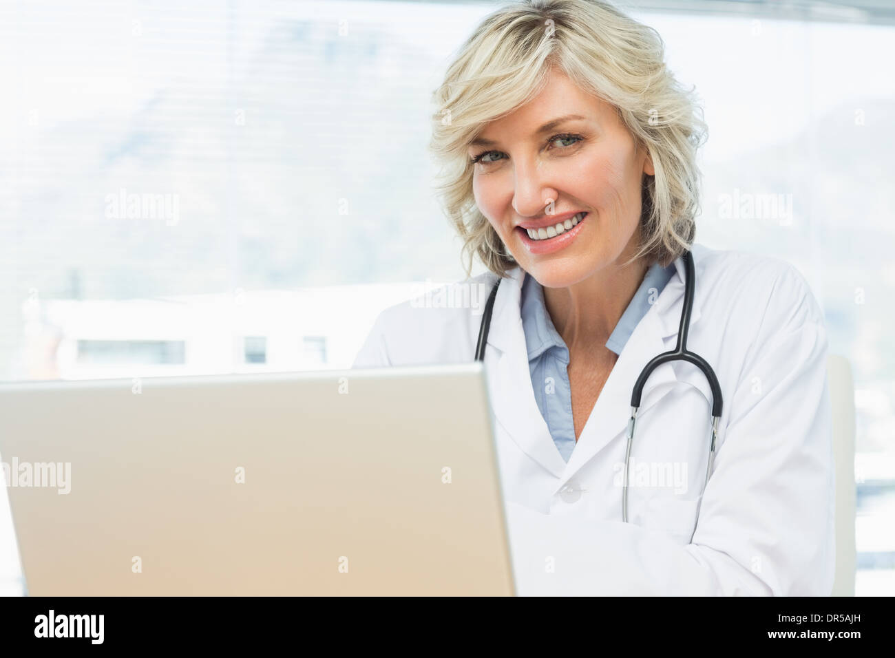 Smiling female doctor using laptop in medical office Stock Photo - Alamy