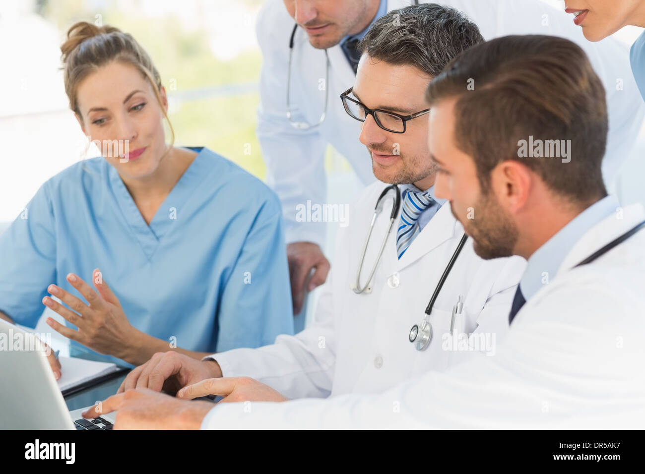 Group of concentrated doctors using laptop together Stock Photo - Alamy