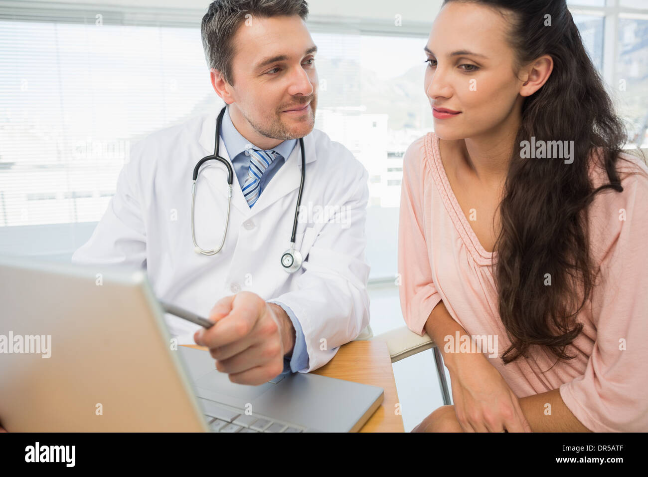 Doctor showing something on laptop to patient in medical office Stock ...