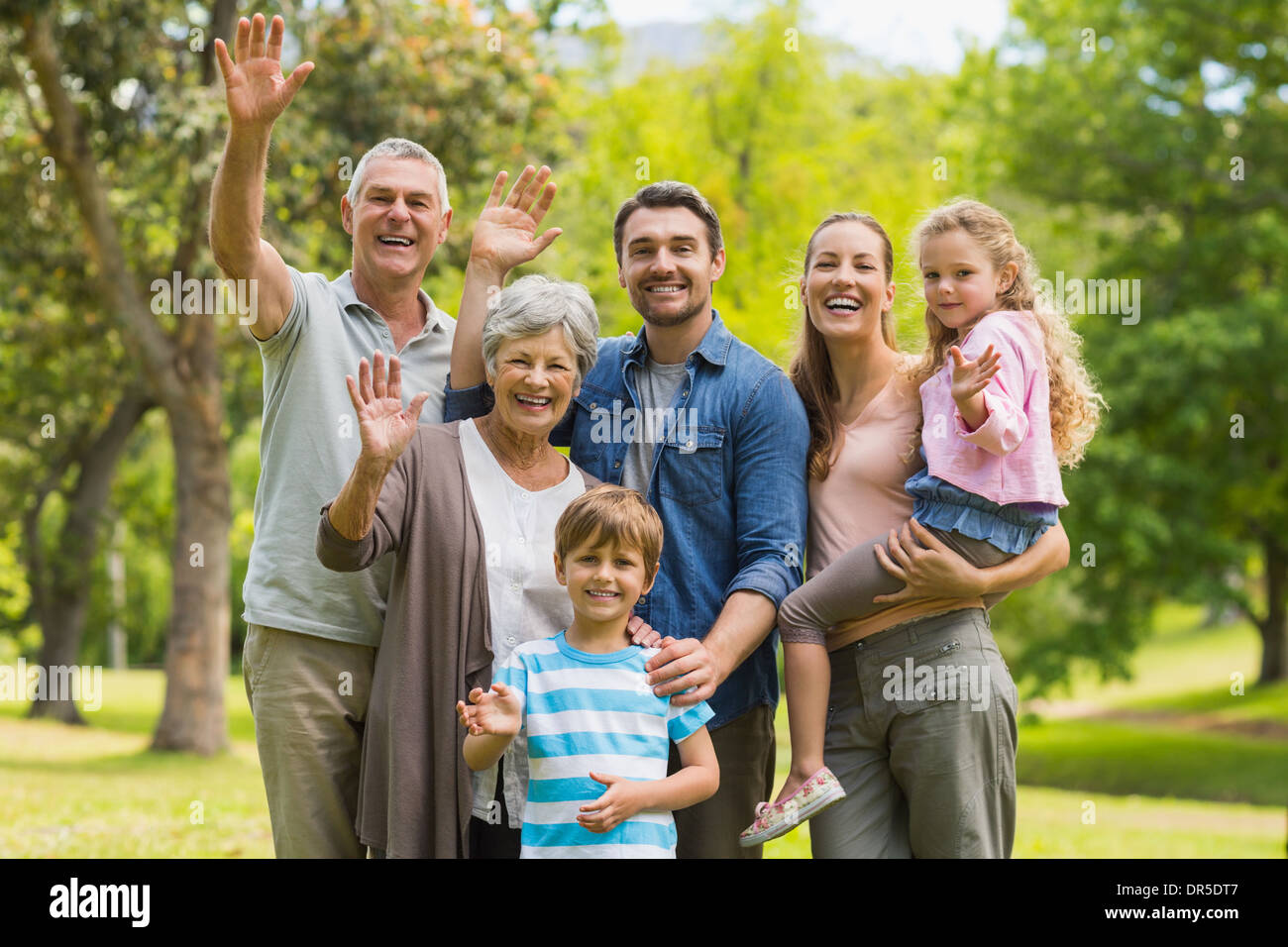 Extended family waving hands in park Stock Photo - Alamy