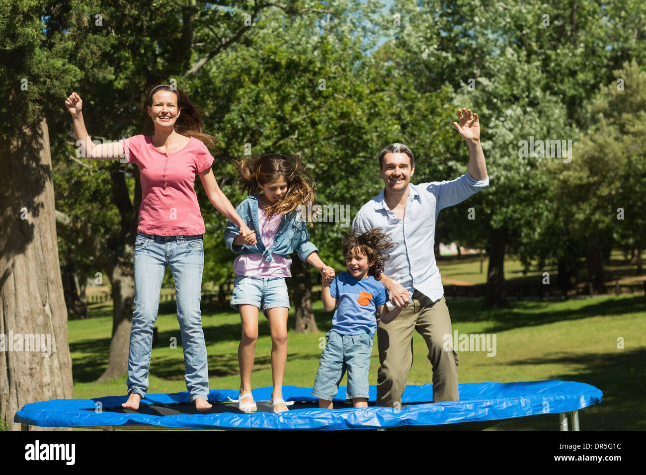 Happy family jumping high on trampoline in park Stock Photo - Alamy