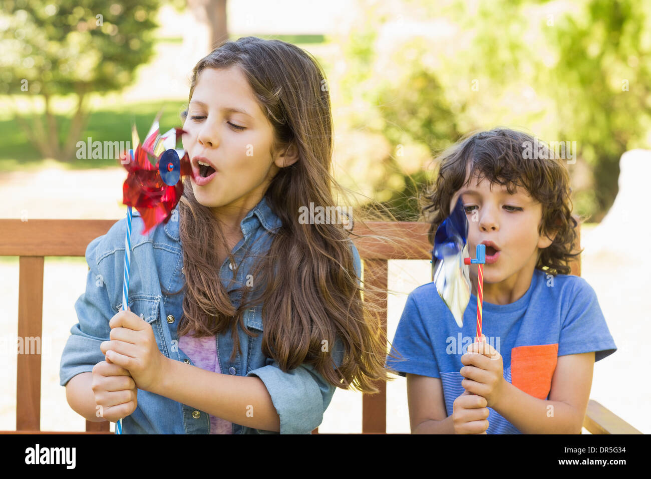 Kids blowing pinwheels on park bench Stock Photo - Alamy