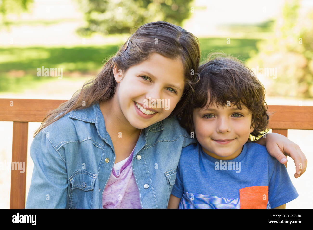 Portrait of cute kids sitting on park bench Stock Photo - Alamy