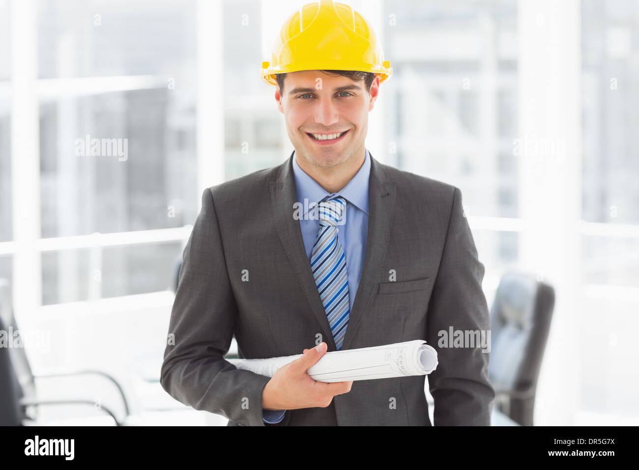 Happy architect holding blueprints smiling at camera Stock Photo - Alamy