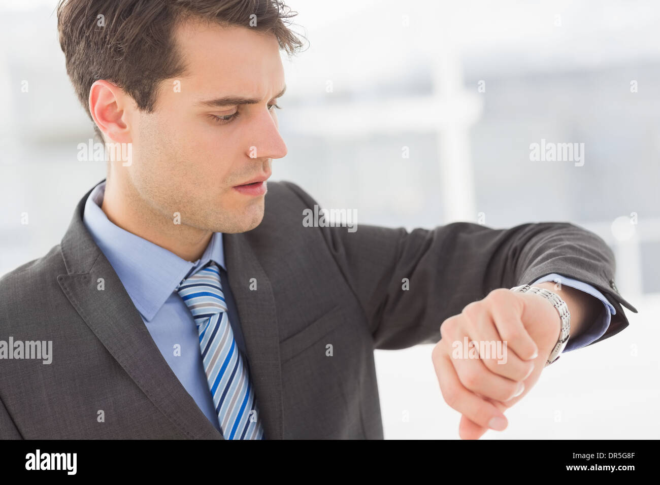 Serious businessman checking the time on his watch Stock Photo - Alamy