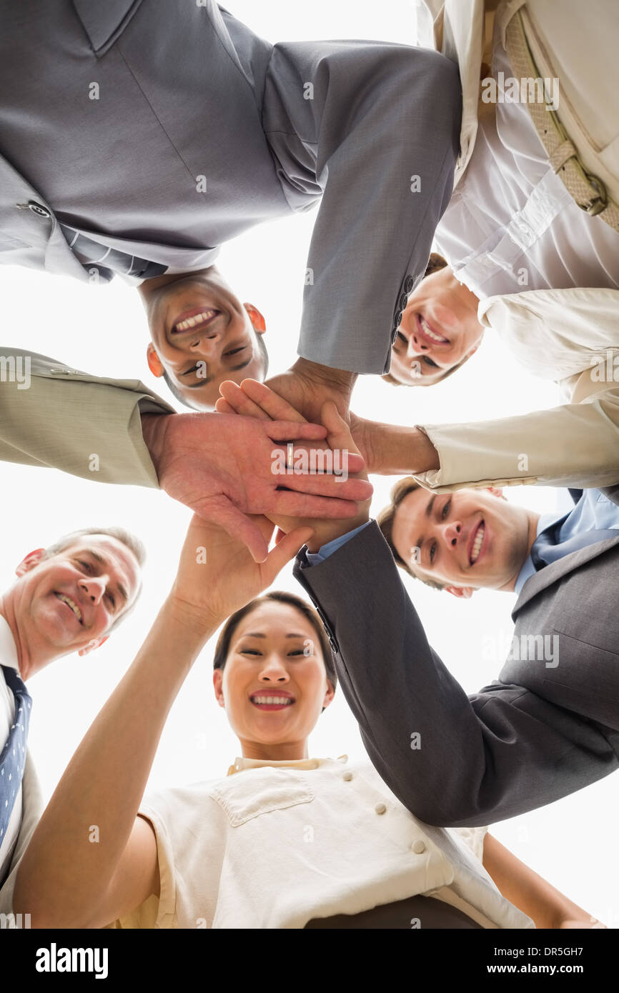 Happy business team looking down at the camera with hands together ...