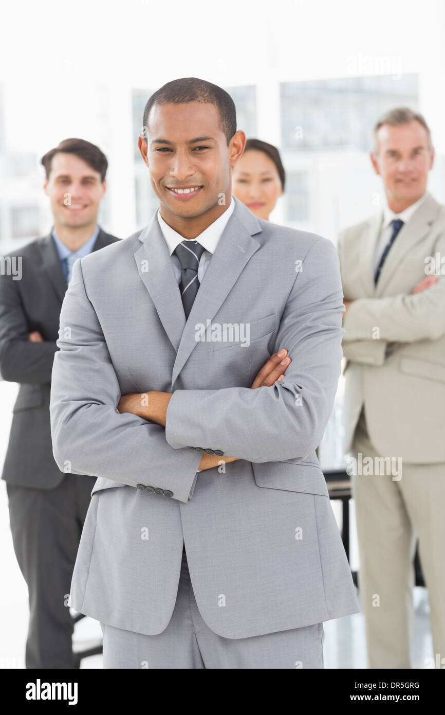 Businessman smiling at camera with team behind him Stock Photo - Alamy