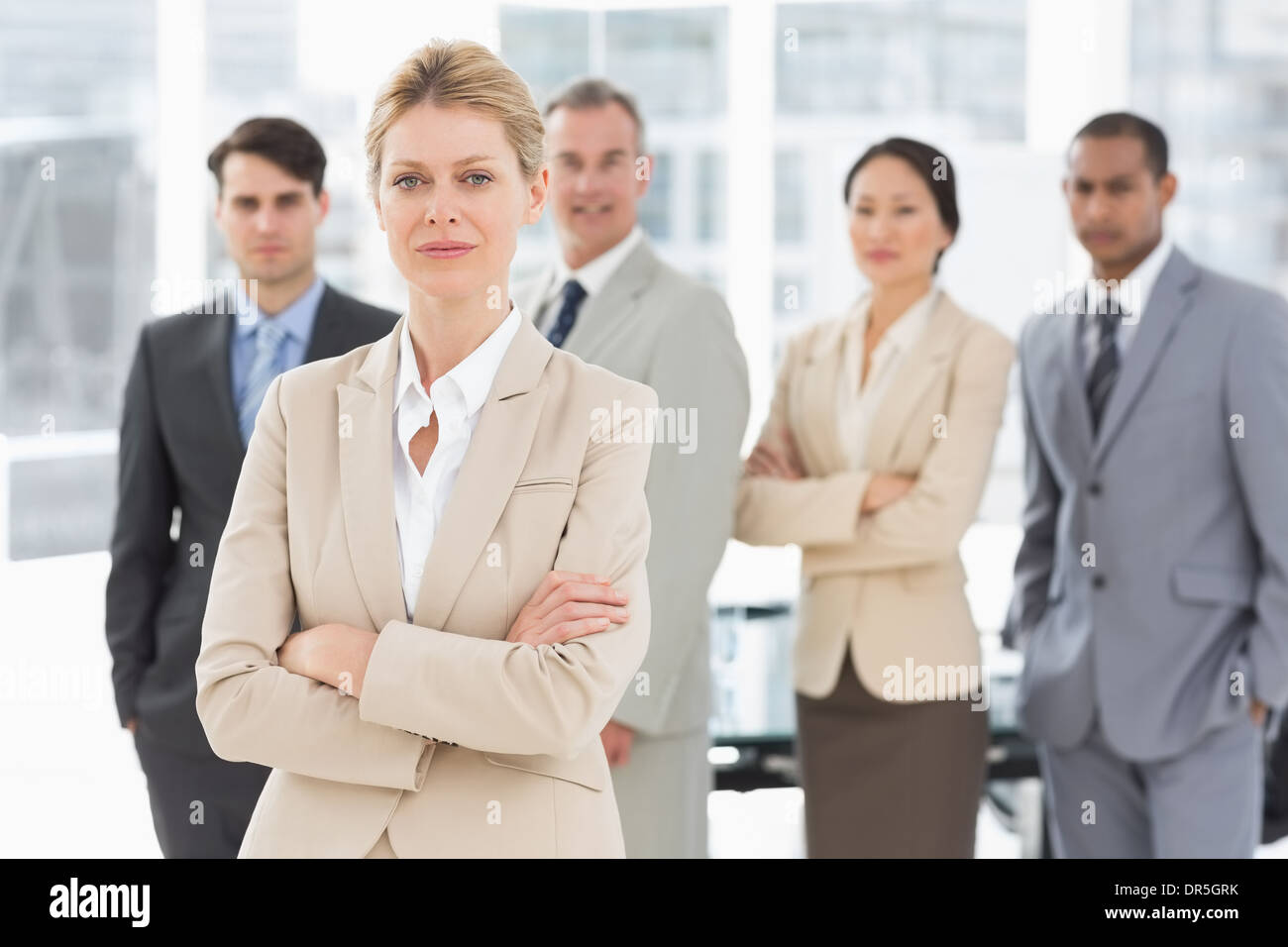 Businesswoman looking at camera with team behind her Stock Photo - Alamy