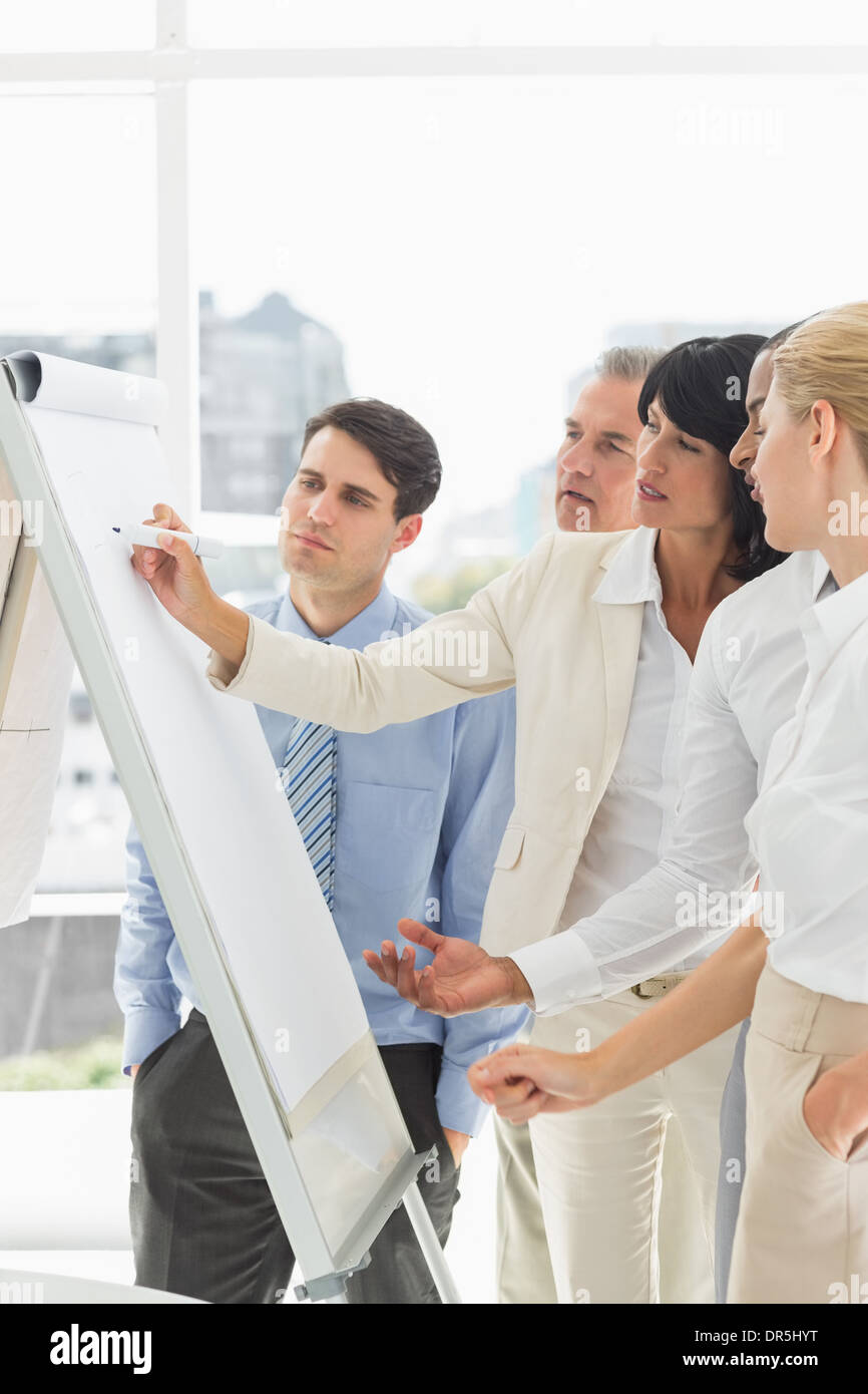 Interested colleagues watching businesswoman writing on whiteboard ...