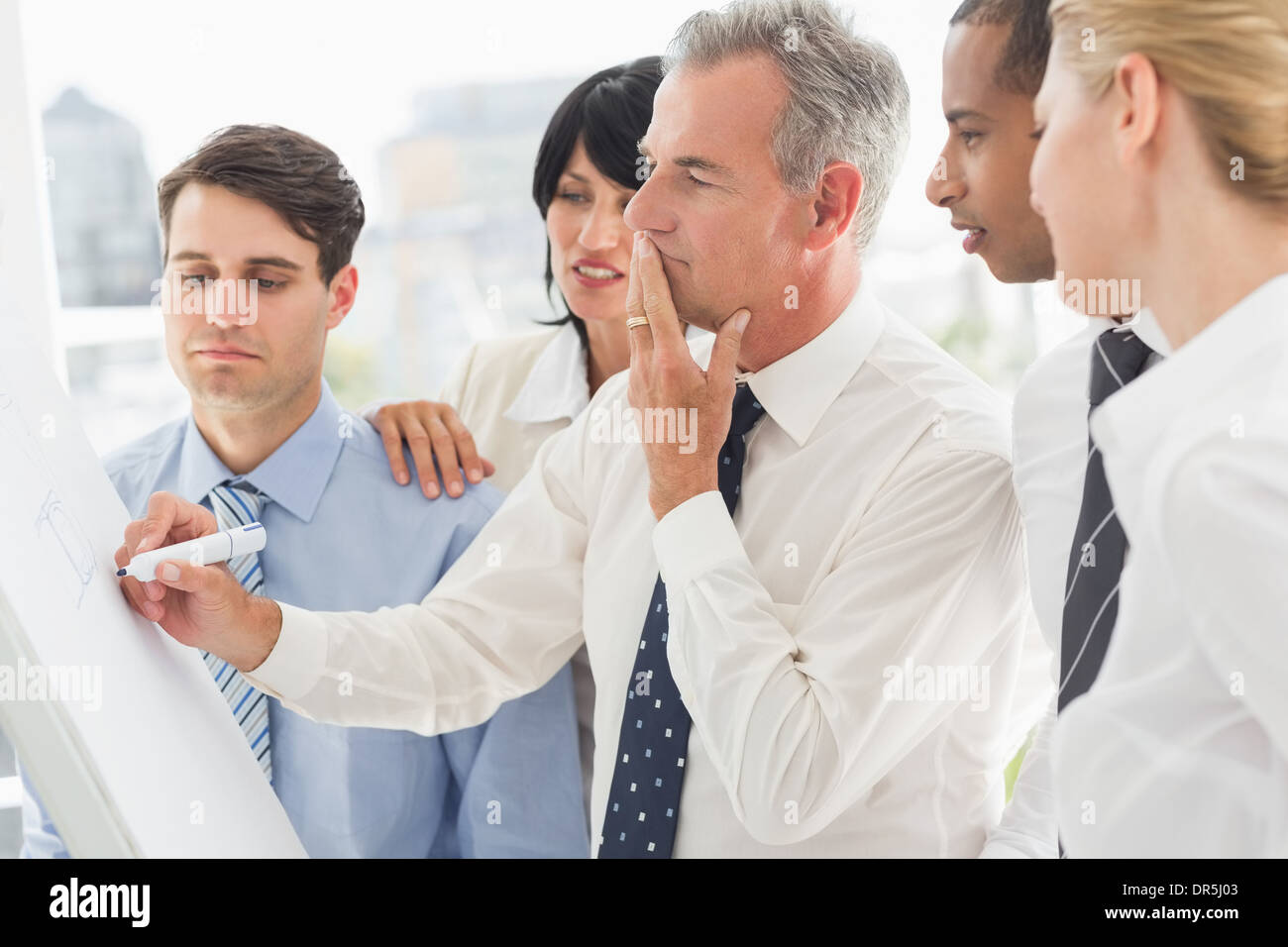 Colleagues watching thinking businessman writing on whiteboard Stock ...
