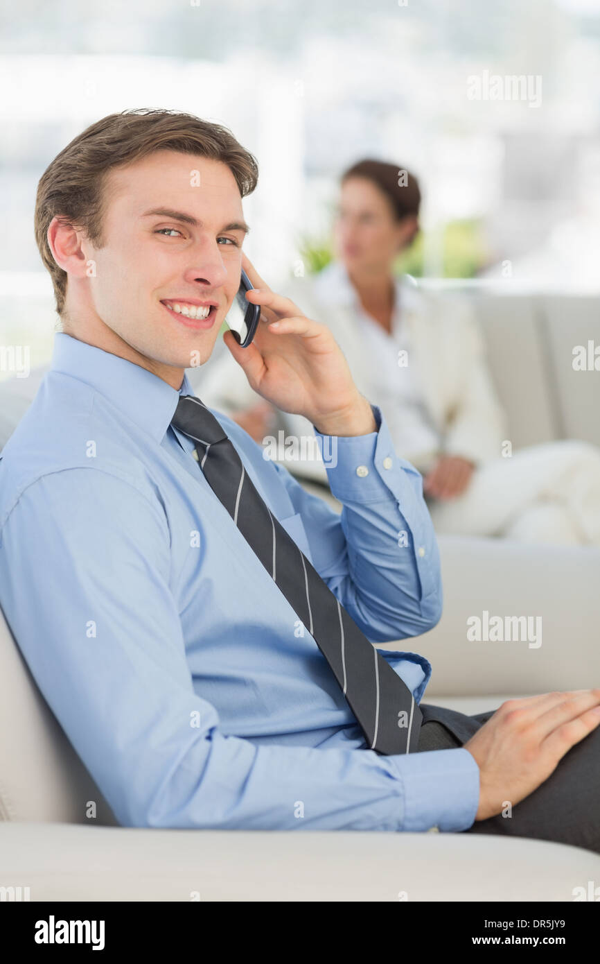 Smiling businessman on the phone sitting on sofa Stock Photo - Alamy