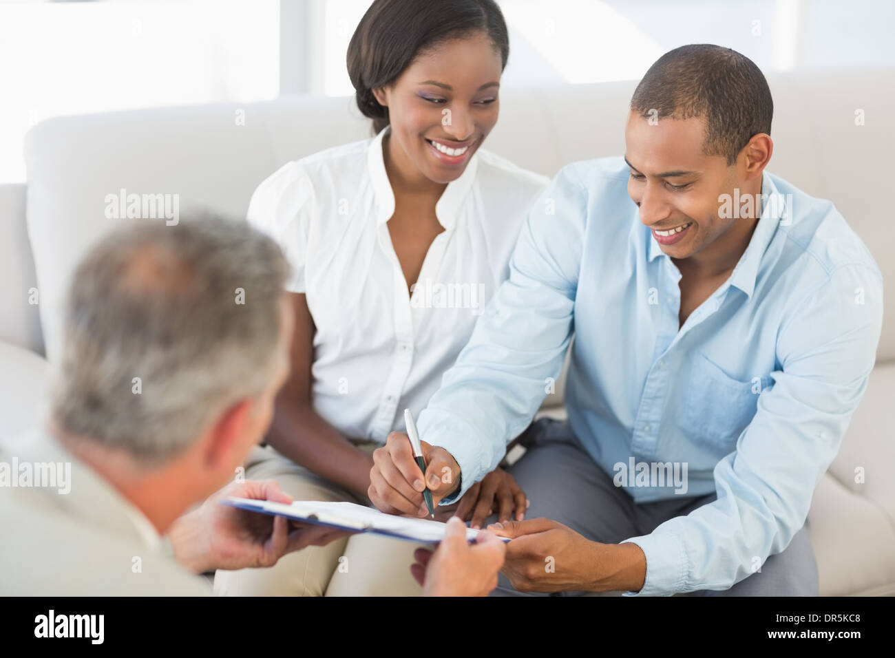 Young smiling couple signing contract on the couch Stock Photo - Alamy