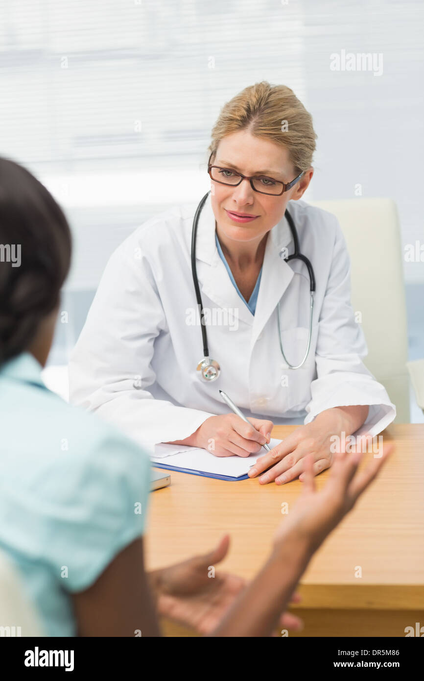 Concerned doctor listening to her patient and taking notes Stock Photo ...