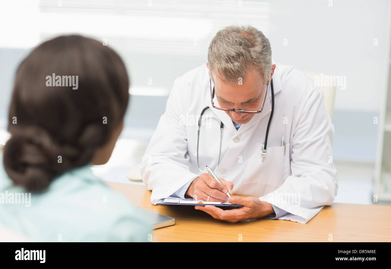 Doctor sitting desk taking notes hi-res stock photography and images ...