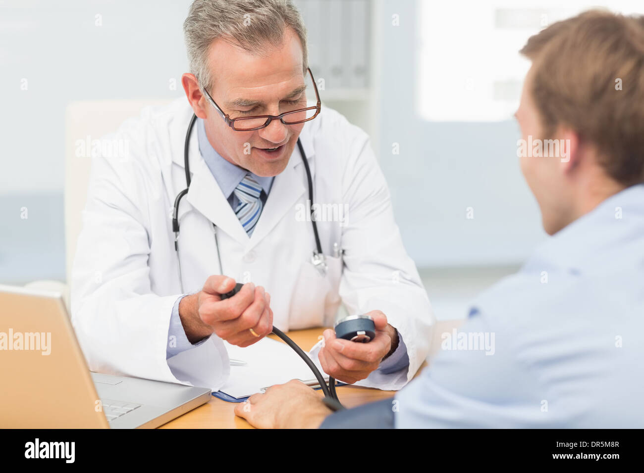Happy doctor taking his patients blood pressure Stock Photo - Alamy