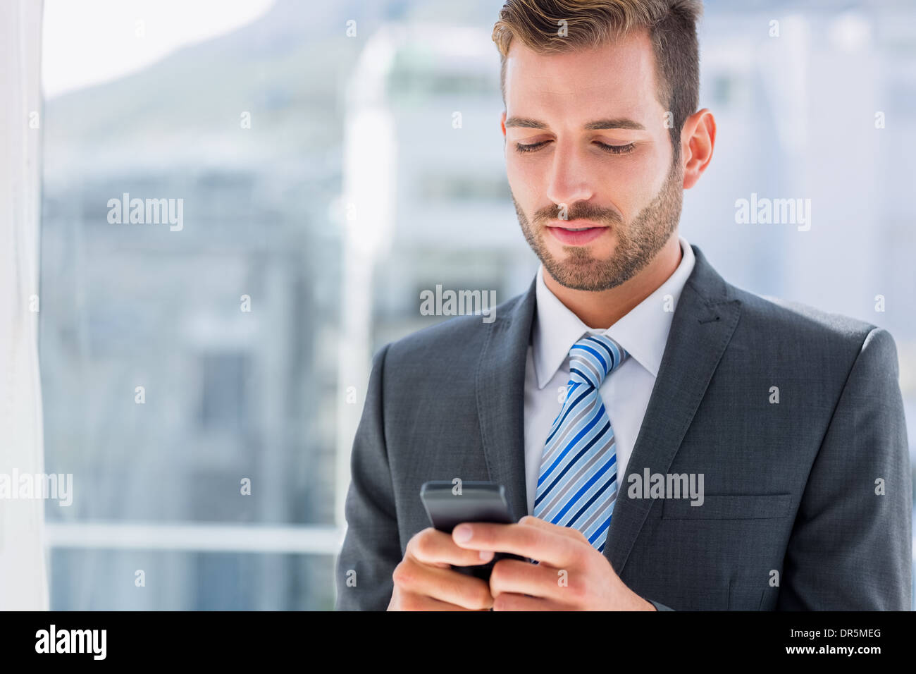 Handsome young businessman text messaging Stock Photo - Alamy