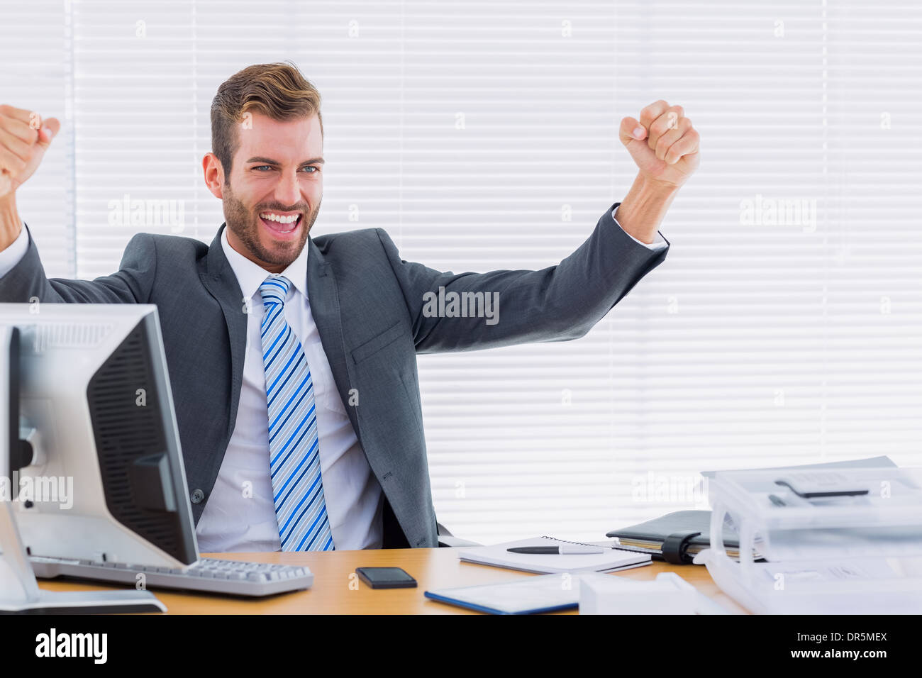 Cheerful businessman clenching fist computer at office desk Stock Photo ...