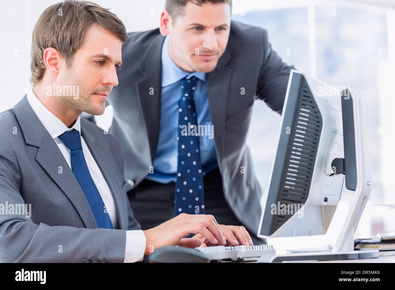 Businessmen using computer at office desk Stock Photo - Alamy