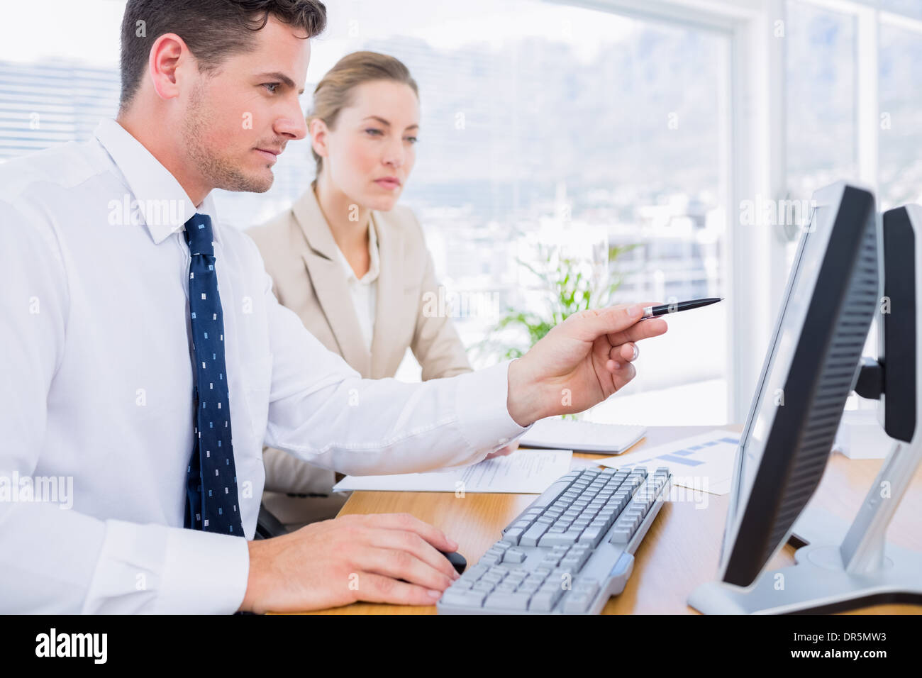 Smartly dressed colleagues using computer Stock Photo - Alamy