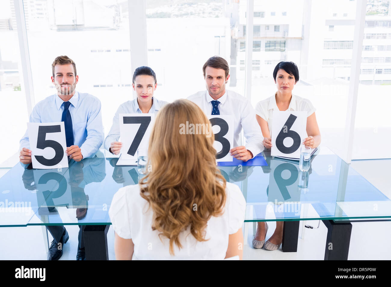 Group of panel judges holding score signs in front of woman Stock Photo ...