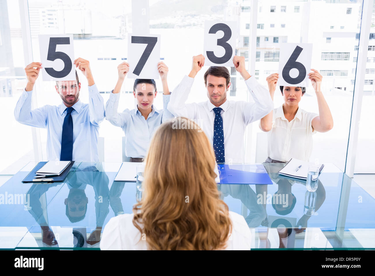 Group of panel judges holding score signs in front of a woman Stock ...