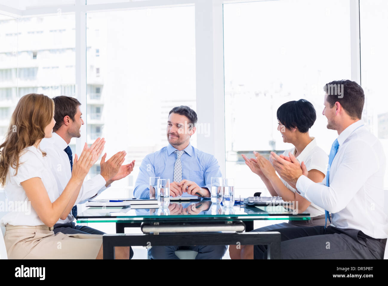 Executives clapping around conference table Stock Photo - Alamy