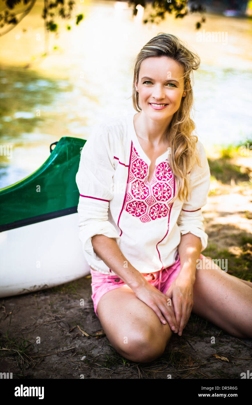 Young woman sitting on the riverside, foothills of the Alps, Bavaria ...
