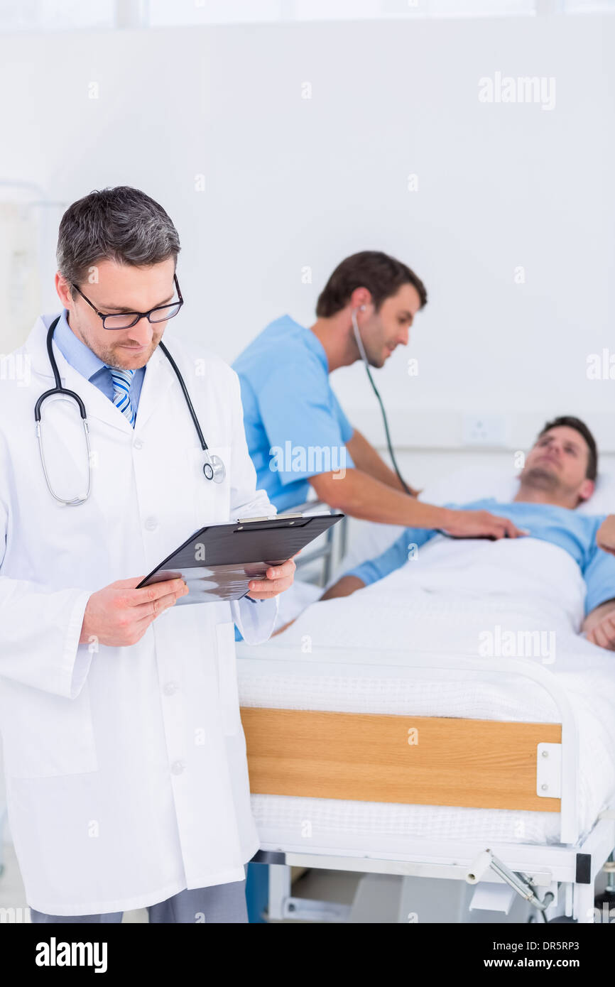 Doctor writing reports with patient and surgeon in background Stock ...