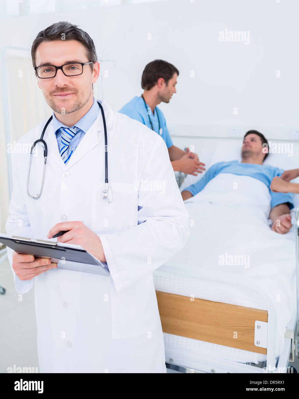 Doctor and surgeon looking at reports with patient in background at ...