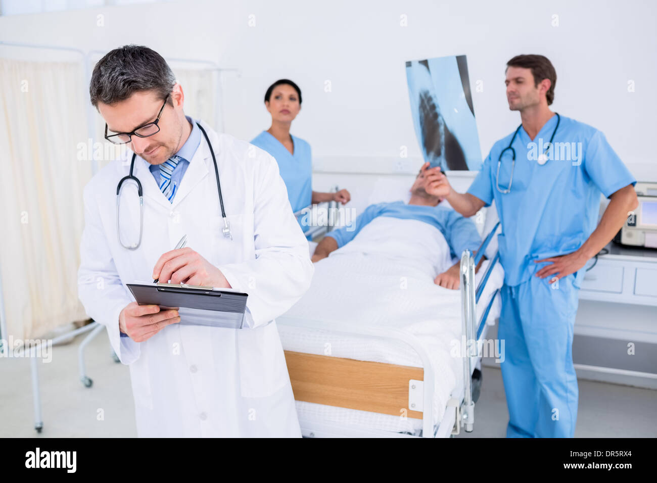 Doctors holding reports by patient at hospital Stock Photo - Alamy