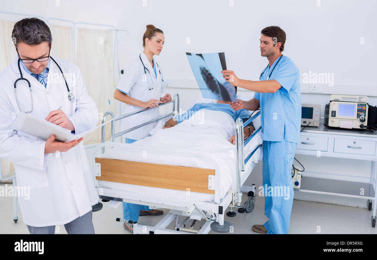 Doctors holding reports by patient in at hospital Stock Photo - Alamy