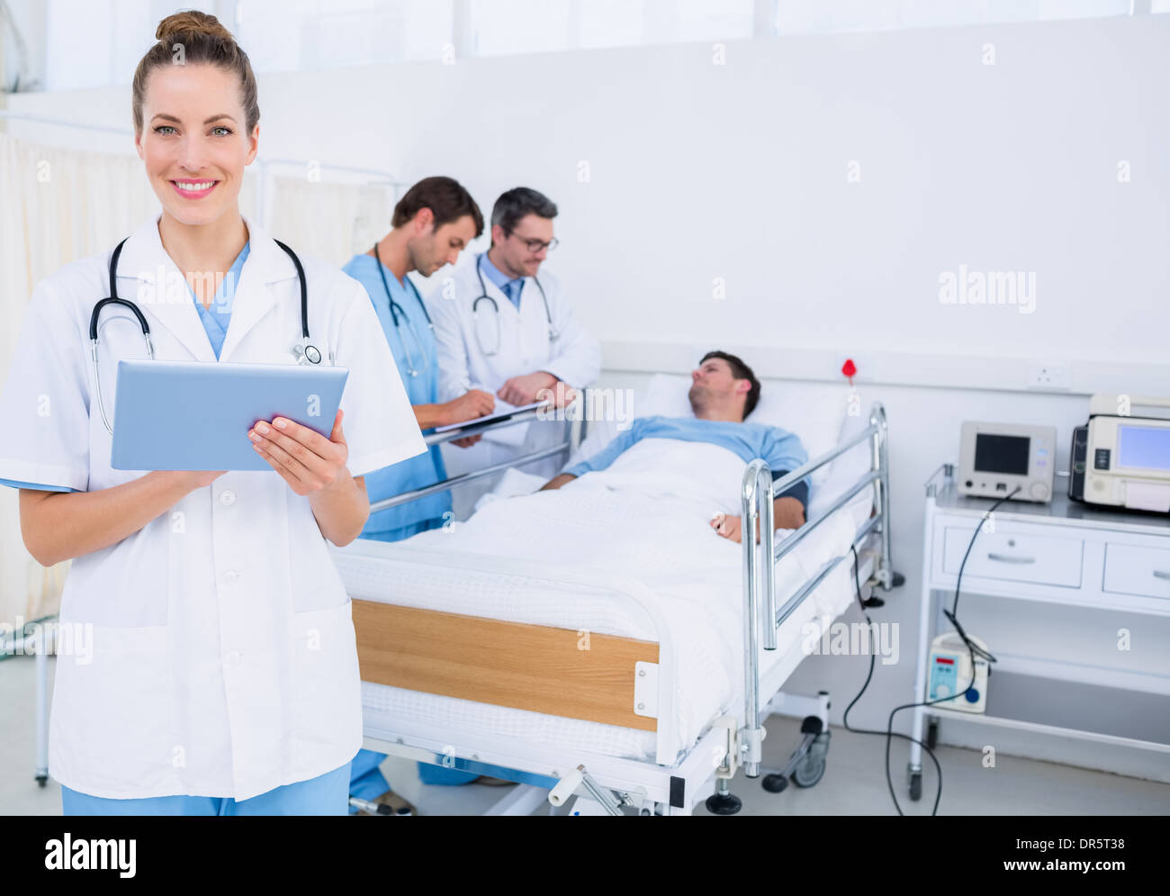Doctor using digital tablet with colleagues and patient behind Stock ...