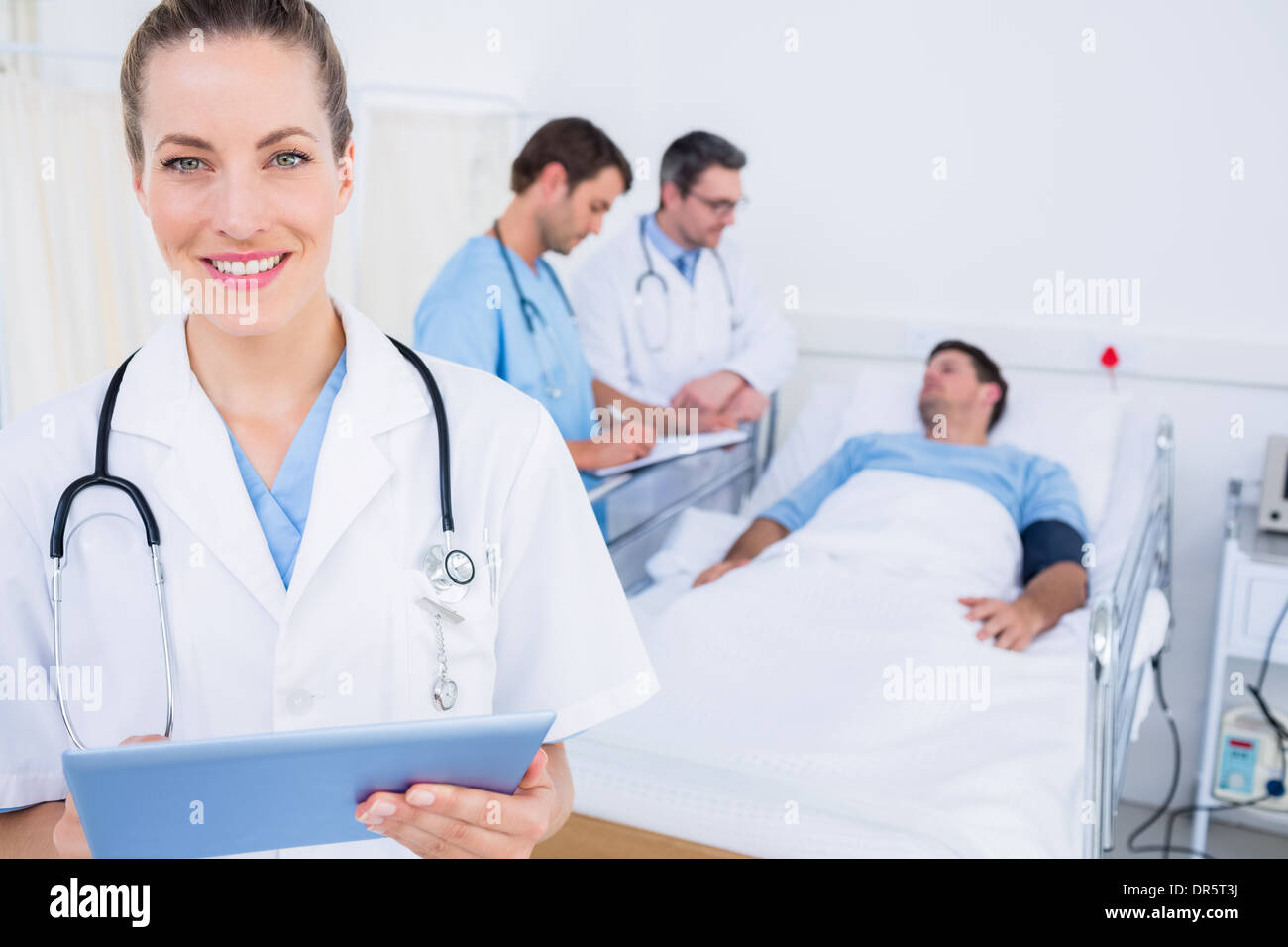 Doctor using digital tablet with colleagues and patient behind Stock ...