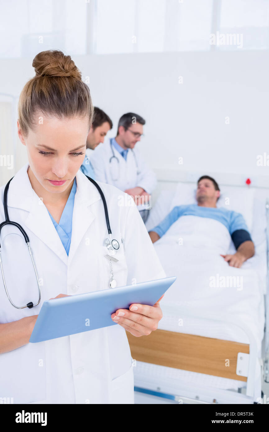 Doctor using digital tablet with colleagues and patient behind Stock ...