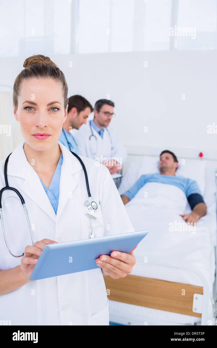 Doctor using digital tablet with colleagues and patient behind Stock ...