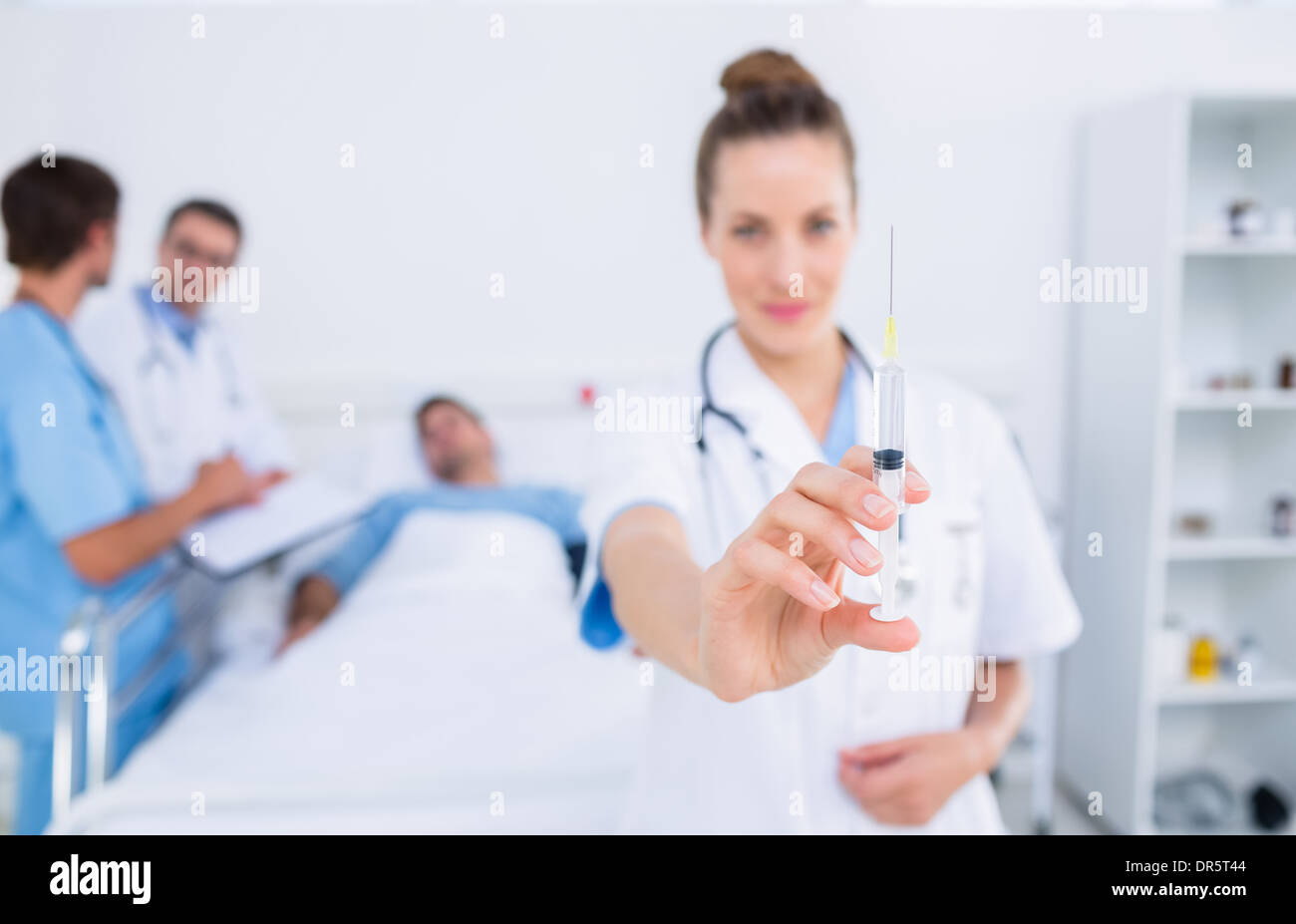 Doctor holding syringe with colleagues and patient in hospital Stock ...