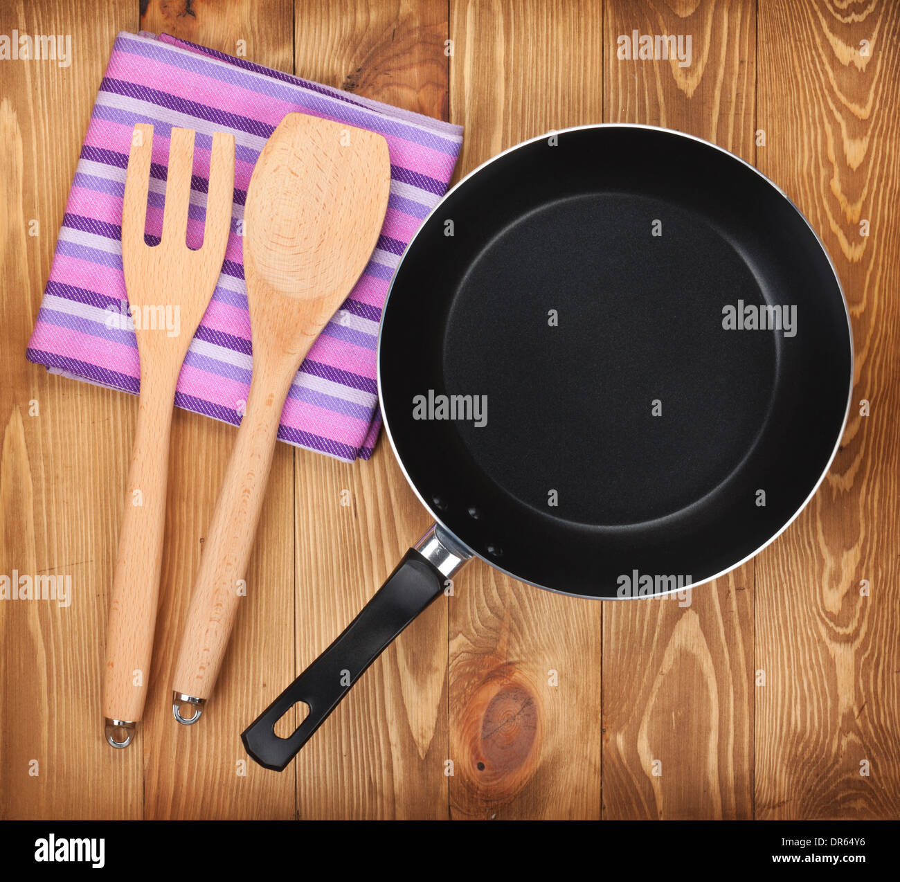 Frying pan and kitchen utensils on wooden table background. View from ...