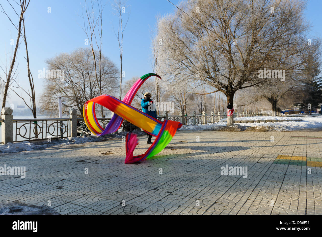 Woman performing a Chinese ribbon dance under the frost covered trees ...