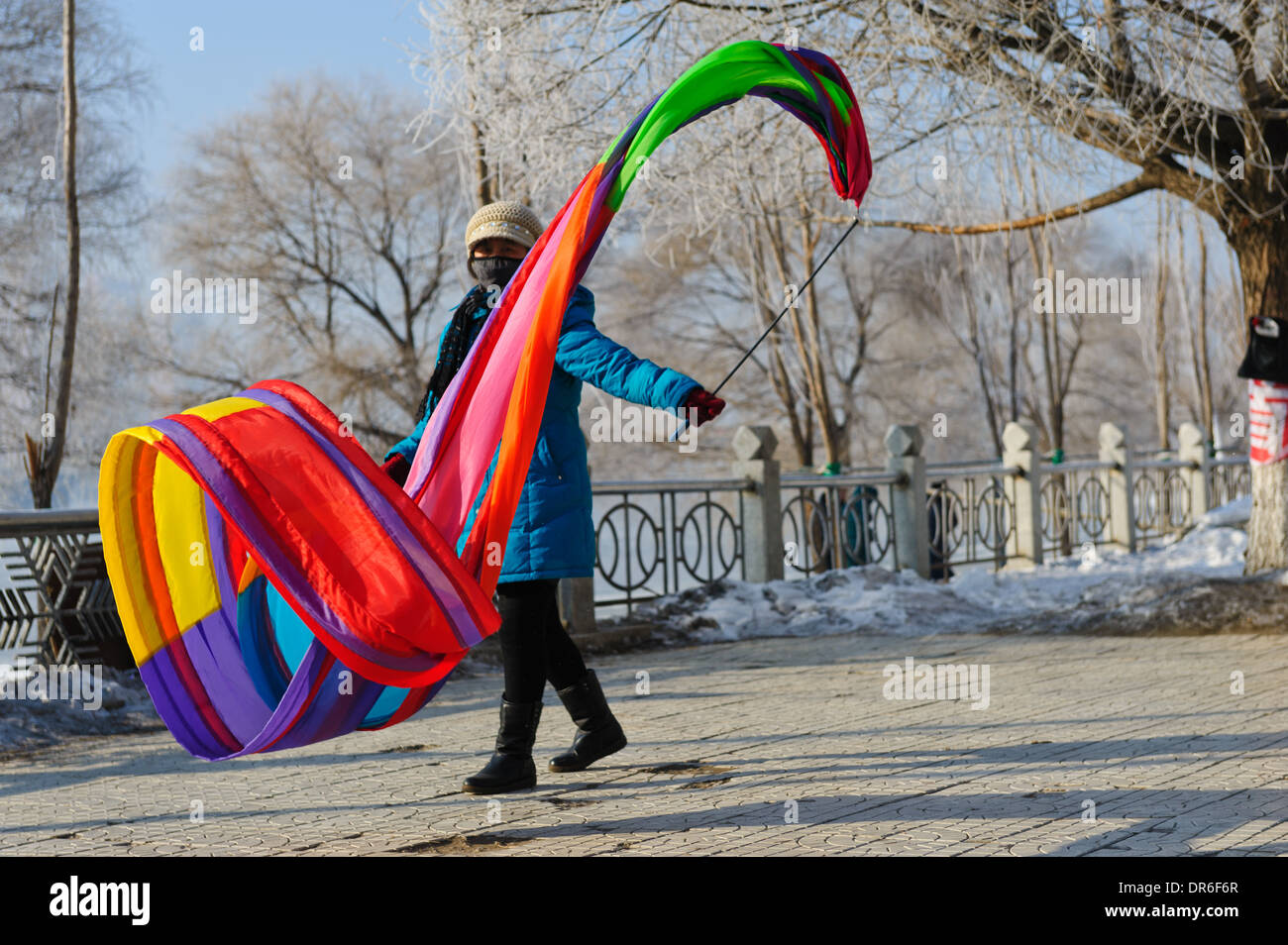 Woman performing a Chinese ribbon dance under the frost covered trees ...