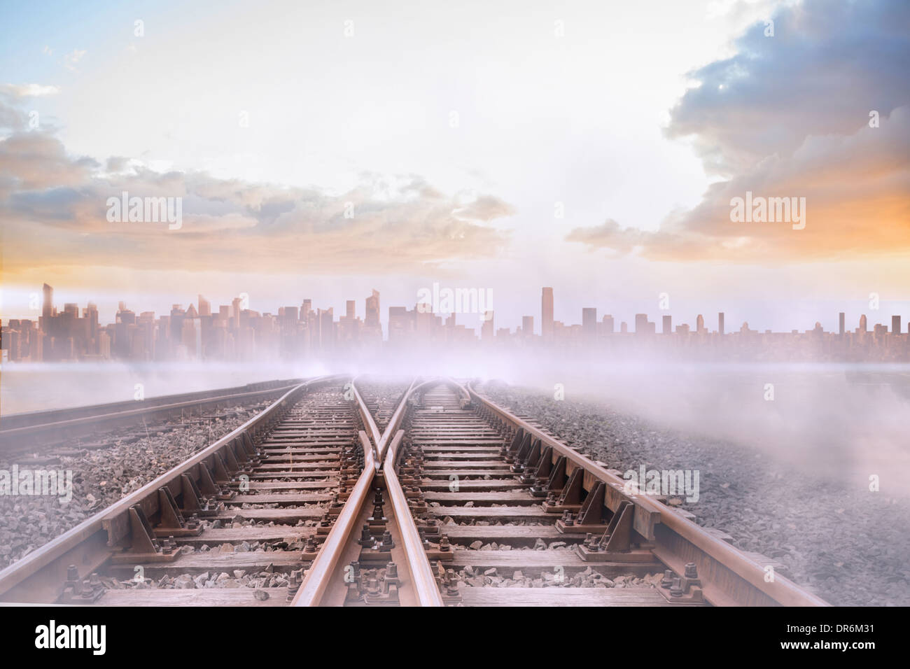 Train tracks leading to misty city on the horizon Stock Photo - Alamy